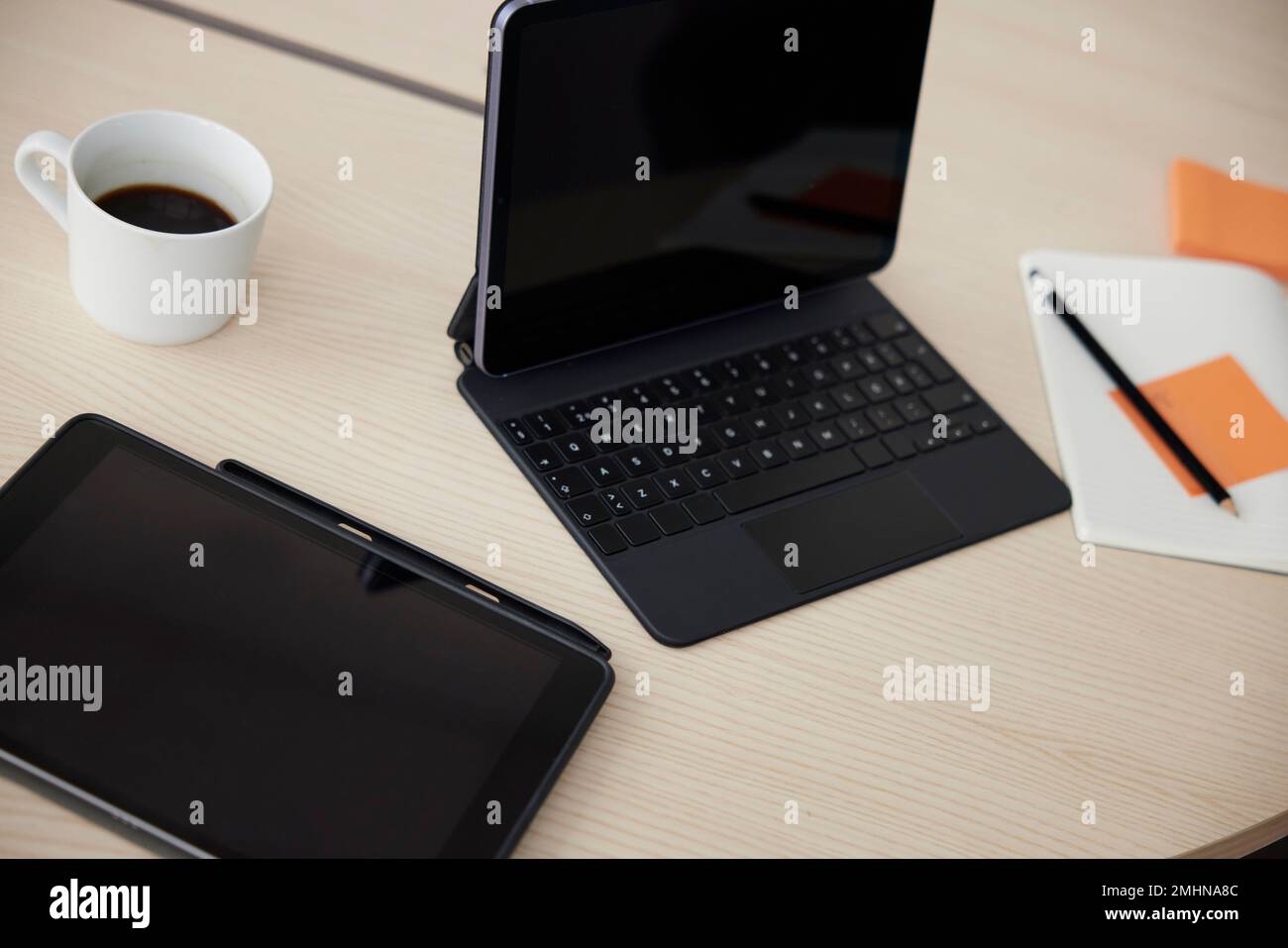 Digital tablets and note pad on desk in office Stock Photo - Alamy