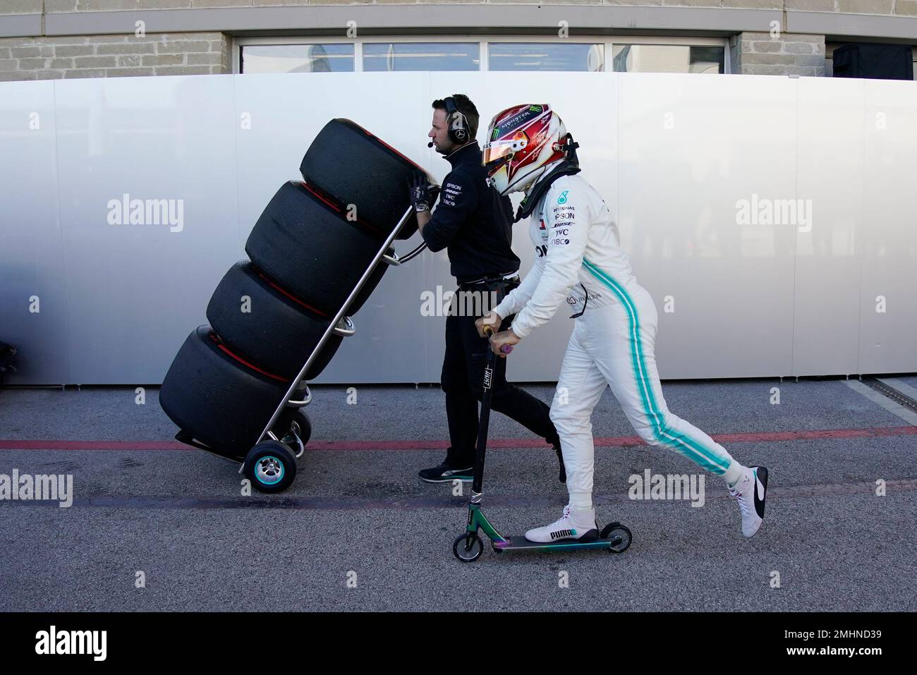 Mercedes driver Lewis Hamilton, of Britain, rides his scooter following ...