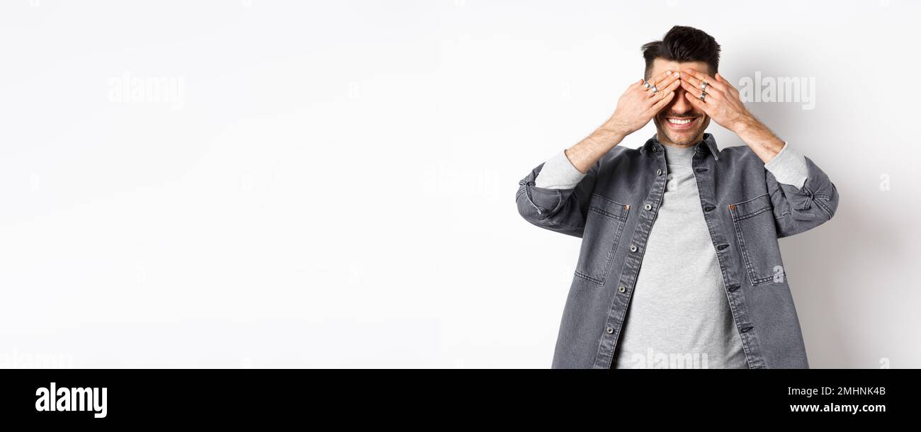 Happy smiling guy waiting with closed eyes for surprise, standing ...