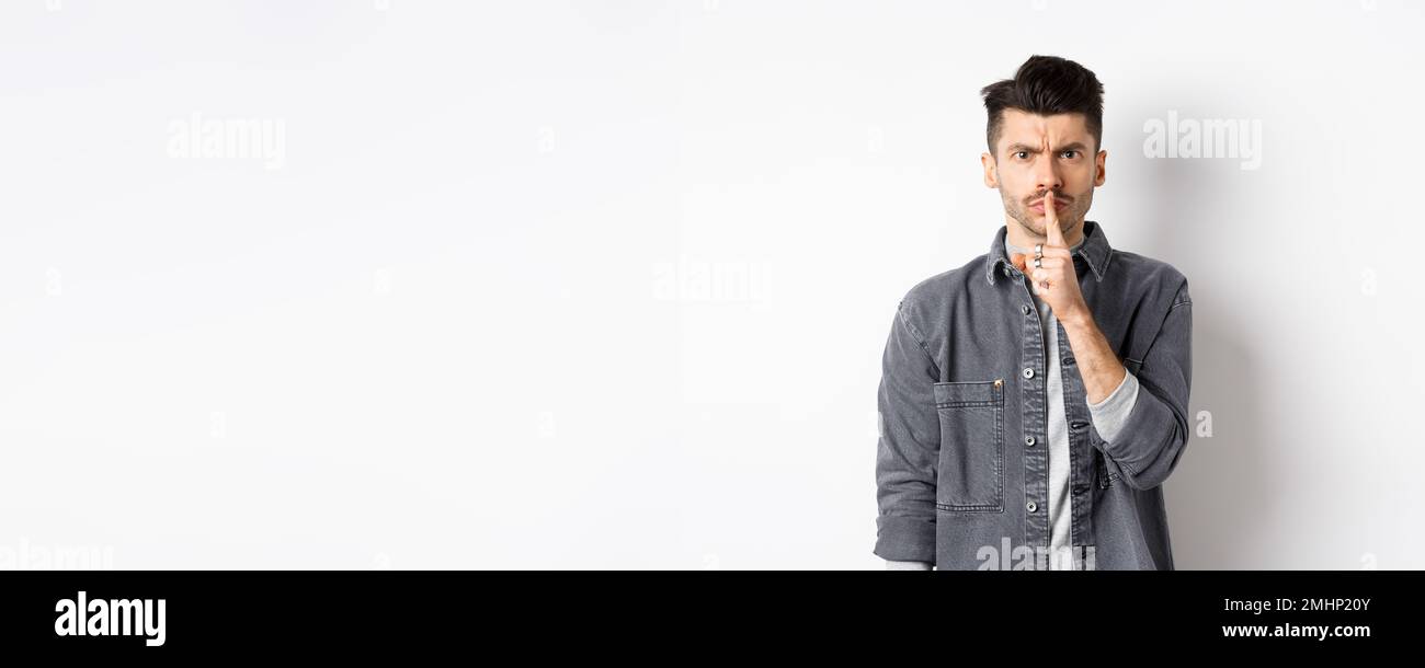 Be quiet. Angry man frowning and shushing, telling to calm down, press ...