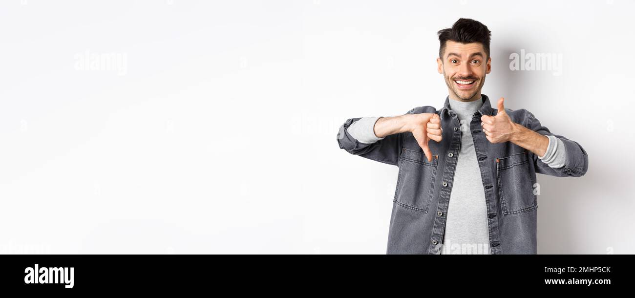 Happy smiling guy showing average gesture, thumbs down up, cant decide ...