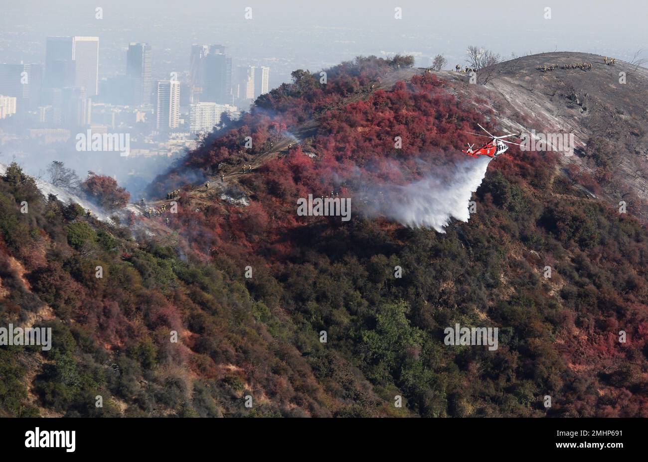 A helicopter drops water as a wildfire called the Getty Fire burns on ...