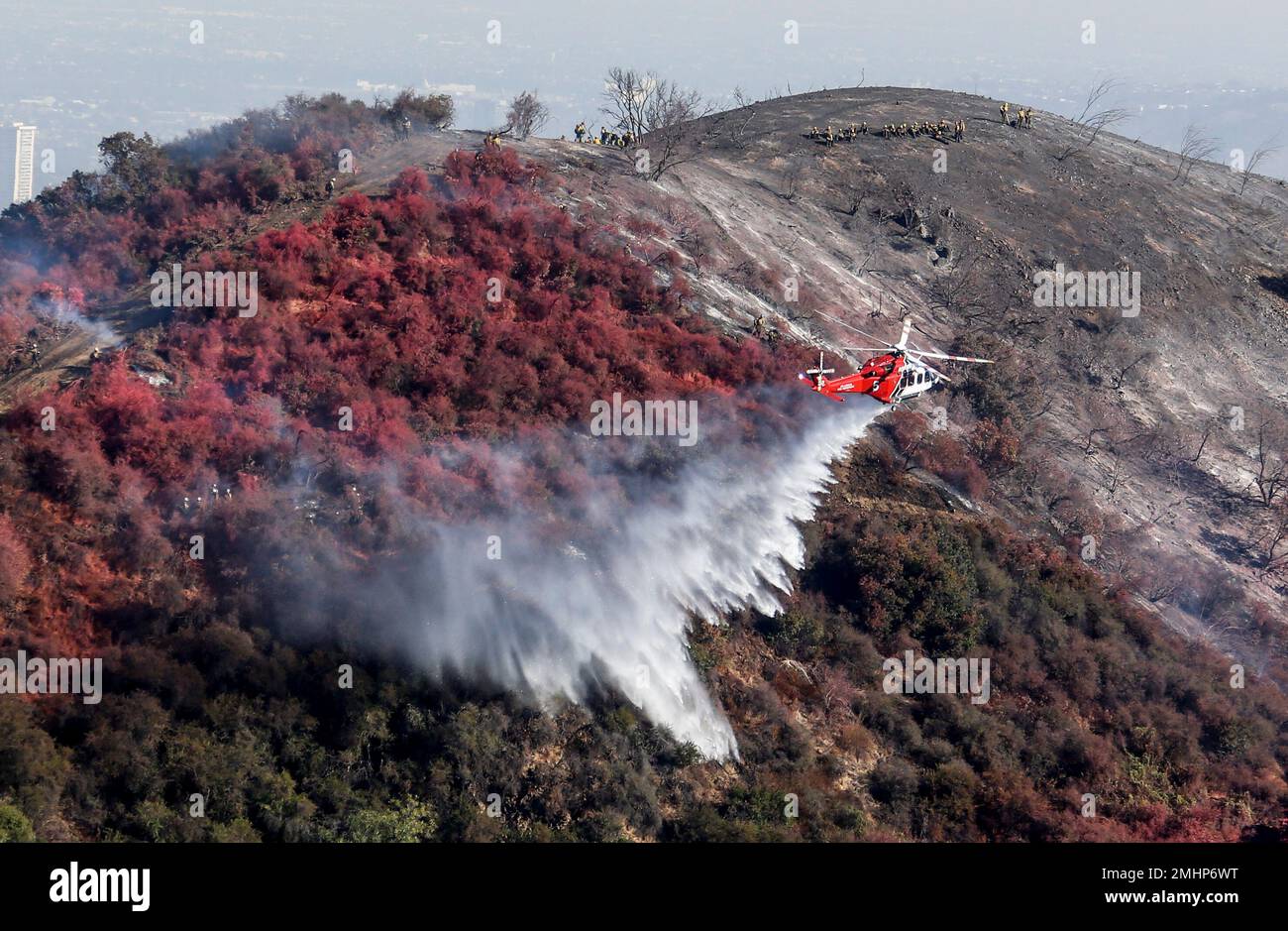 A helicopter drops water as a wildfire called the Getty fire burns on ...
