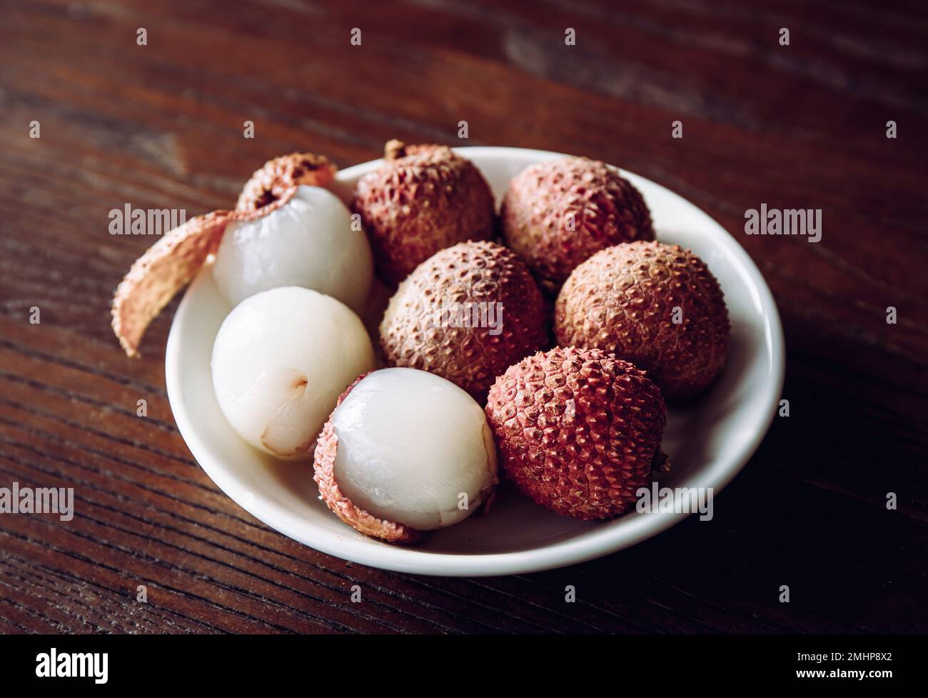 Tropical fruit Lychee known as Litchi chinensis berries on plate, dark ...