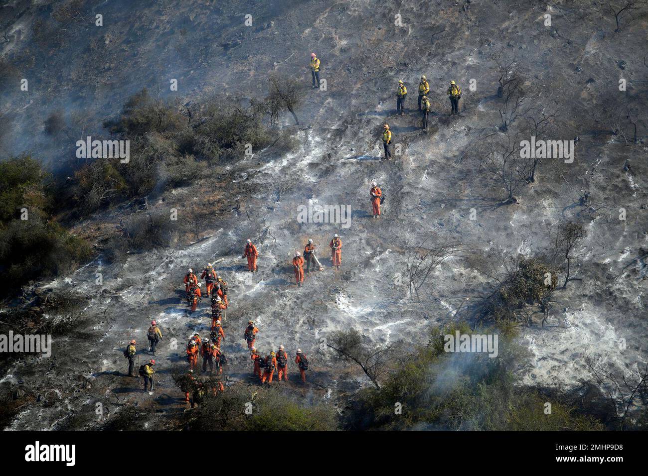 Hand crews work a wildfire-damaged hillside as the Getty fire burns on ...