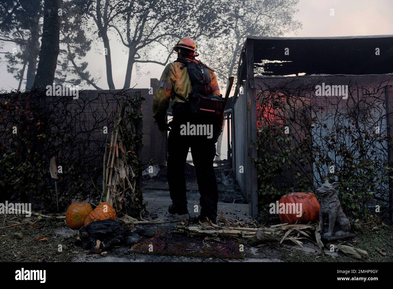 A firefighter works to clear a house destroyed by a wildfire called the ...