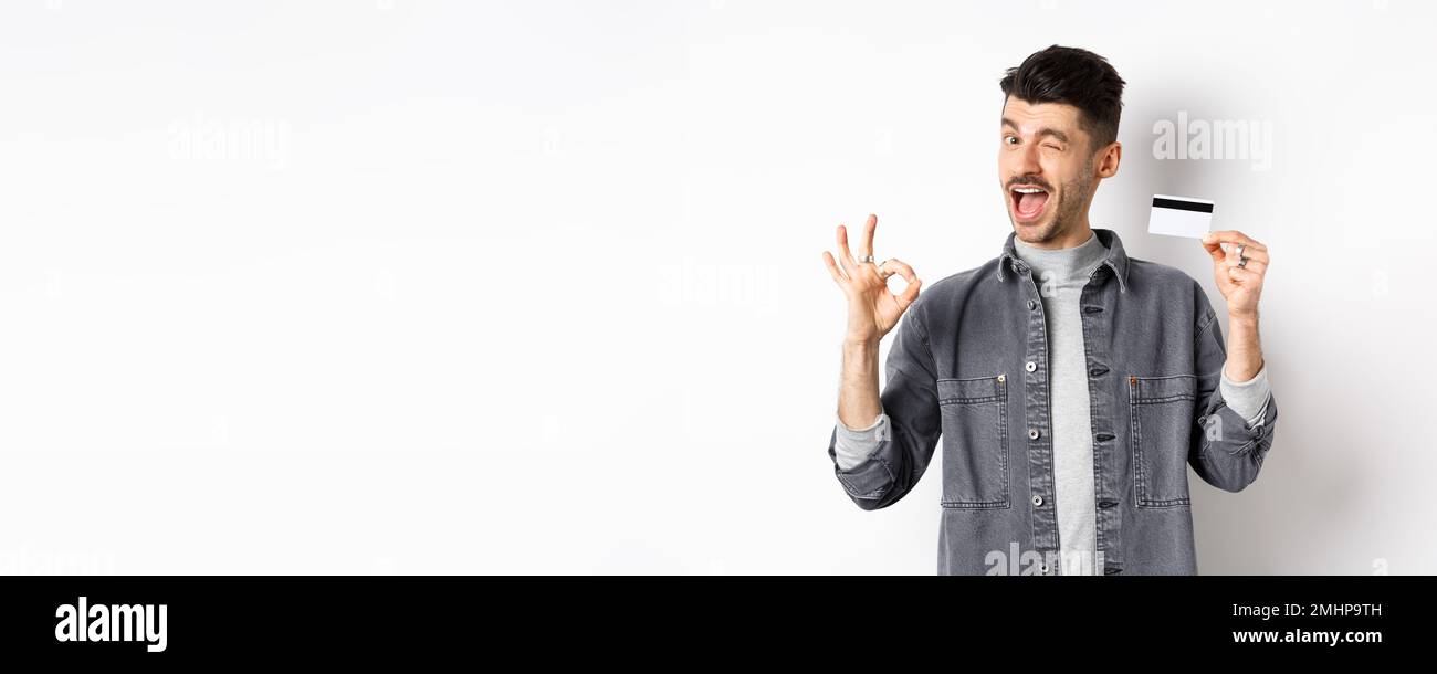 Very good. Smiling guy with plastic credit card showing okay sign ...