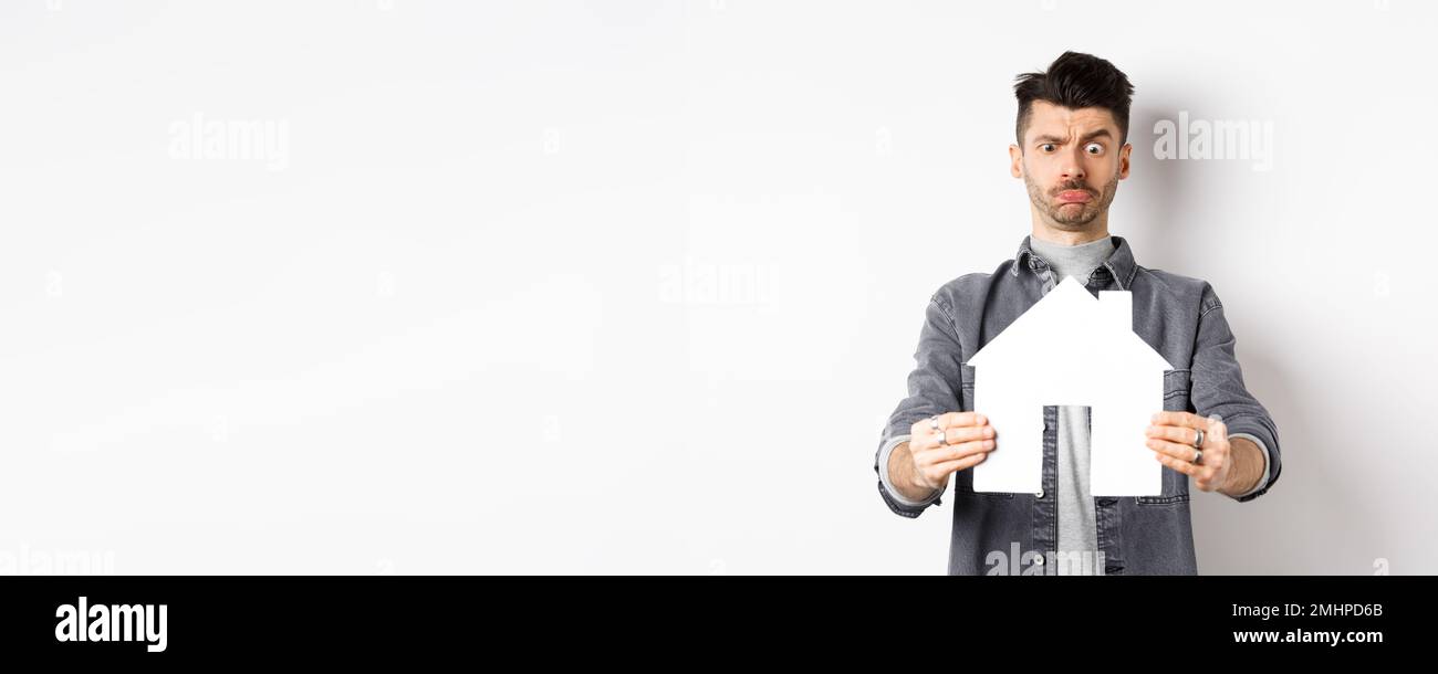 Real estate and insurance concept. Confused guy look at paper house ...