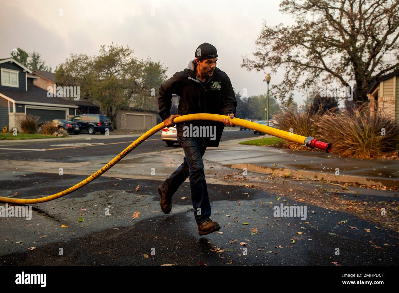 Mike Costlow prepares to hose down a neighbor's home as a wildfire ...