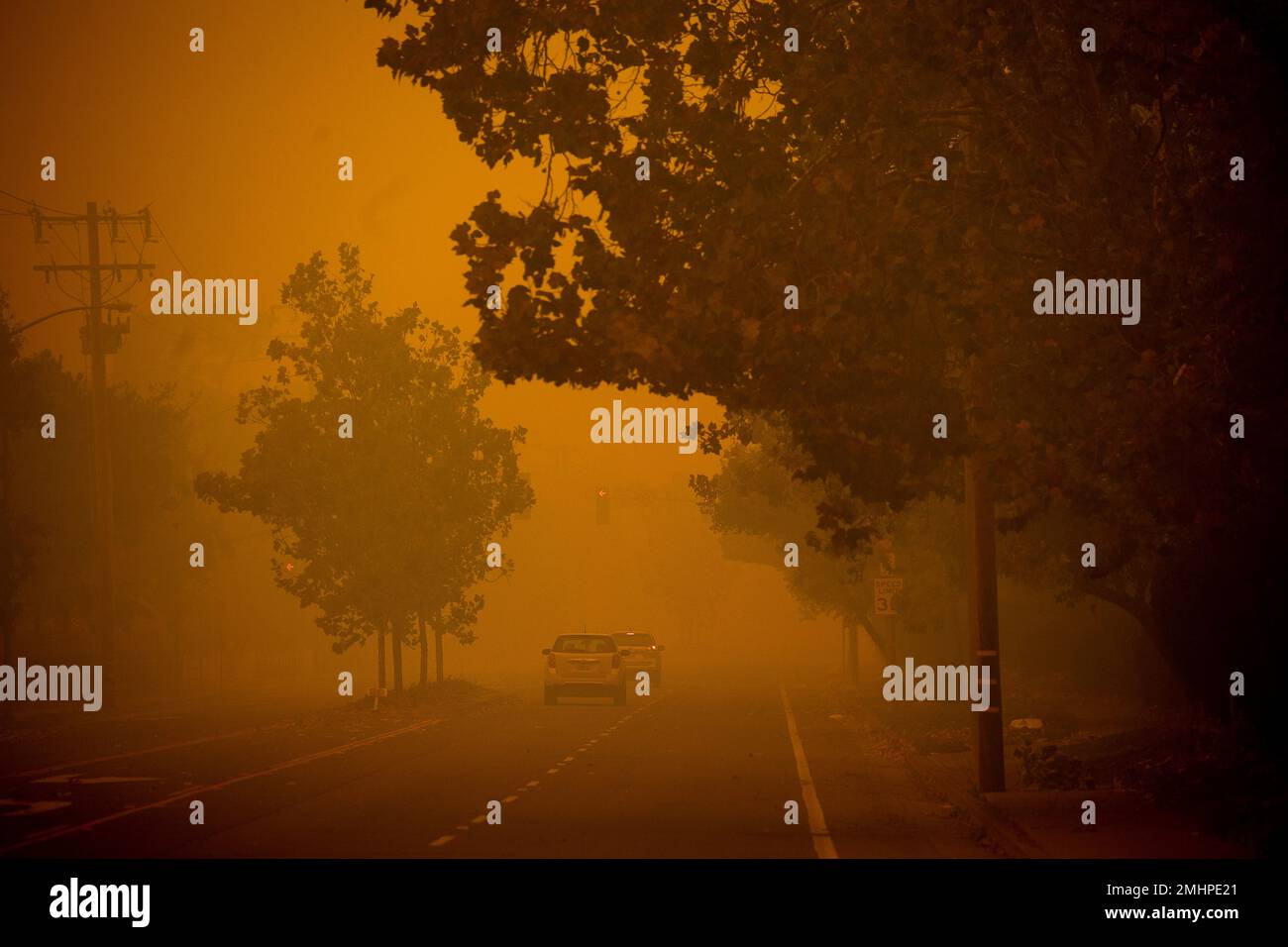 A car drives along a smoke filled street as a wildfire called the ...