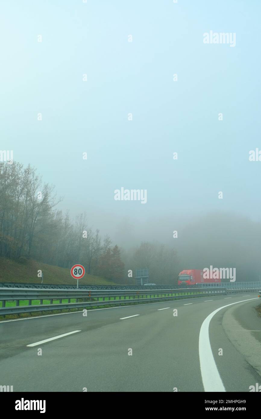 car driving on a highway covered with strong fog. Red truck driving ...