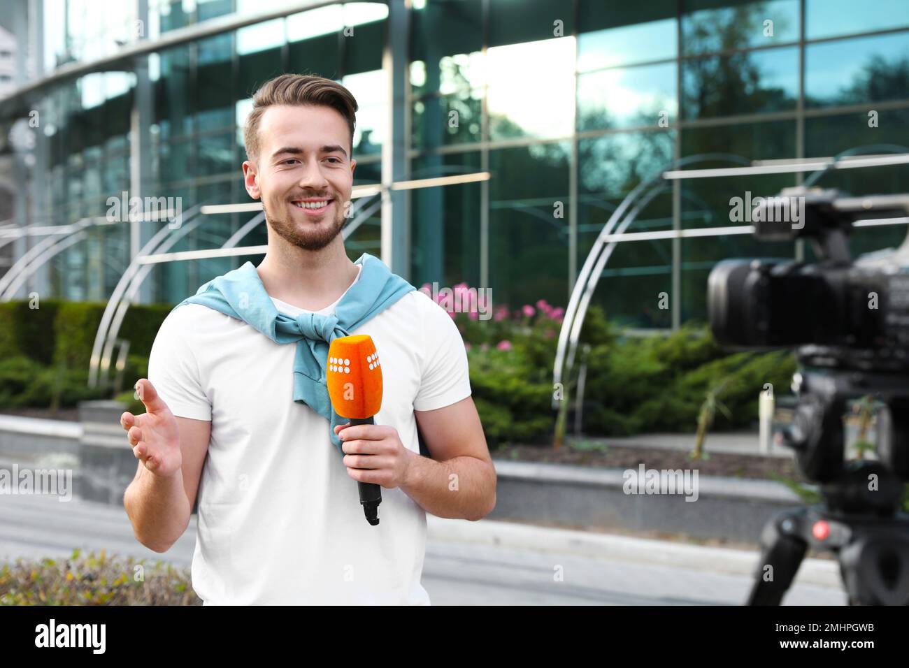 Young male journalist with microphone working on city street Stock ...