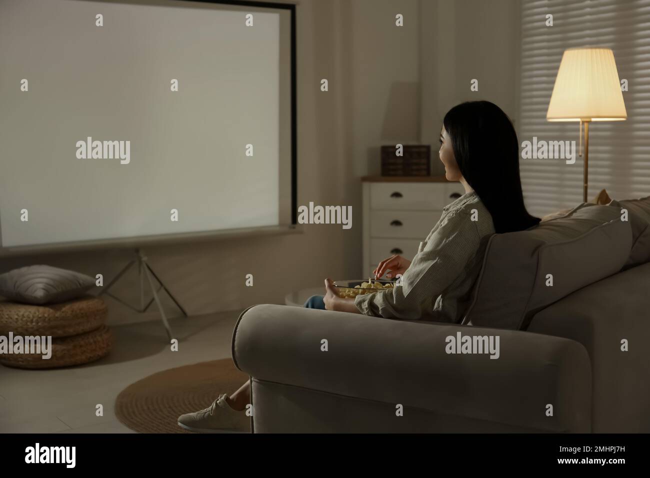 Young woman watching movie using video projector at home Stock Photo ...