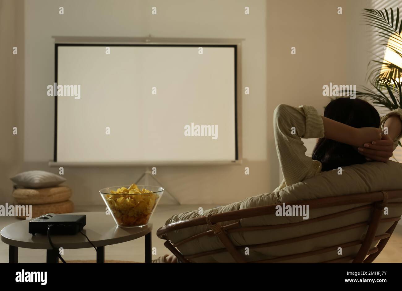 Young woman watching movie using video projector at home Stock Photo ...