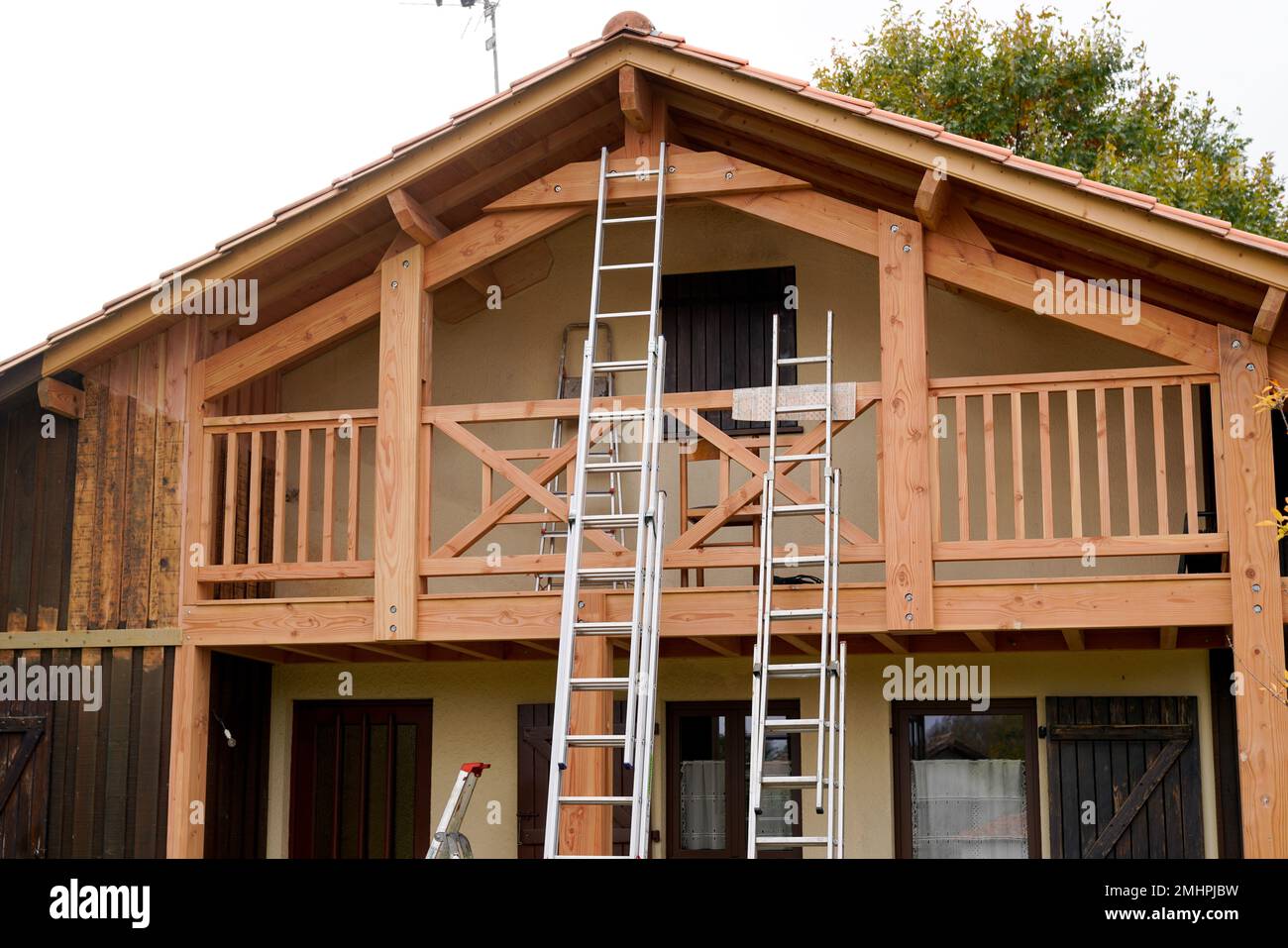 painter ladder painting the wooden beams and railings of the house ...