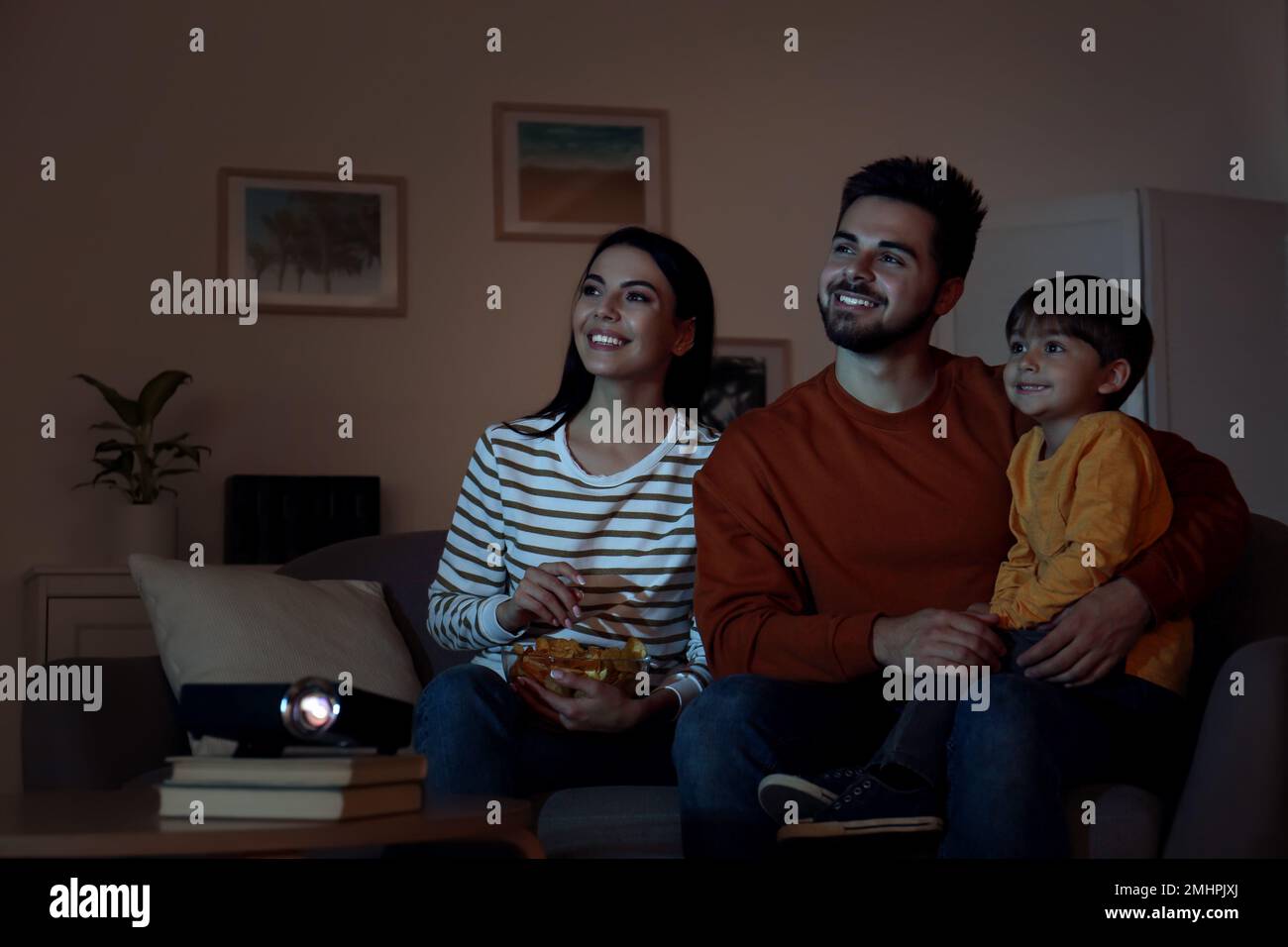 Family watching movie using video projector at home Stock Photo - Alamy