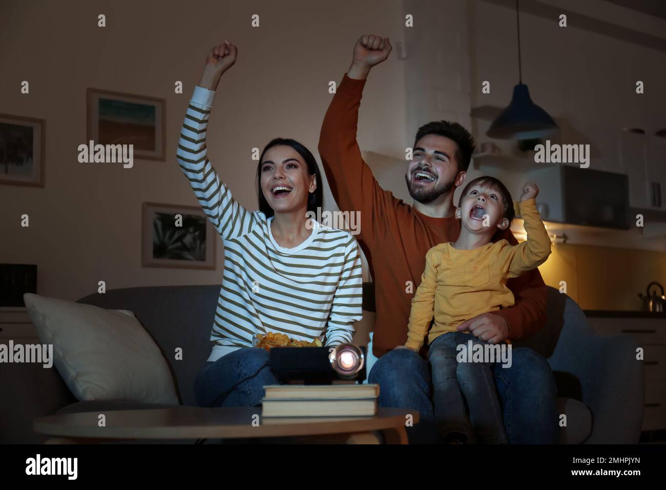 Emotional family watching TV using video projector at home Stock Photo ...