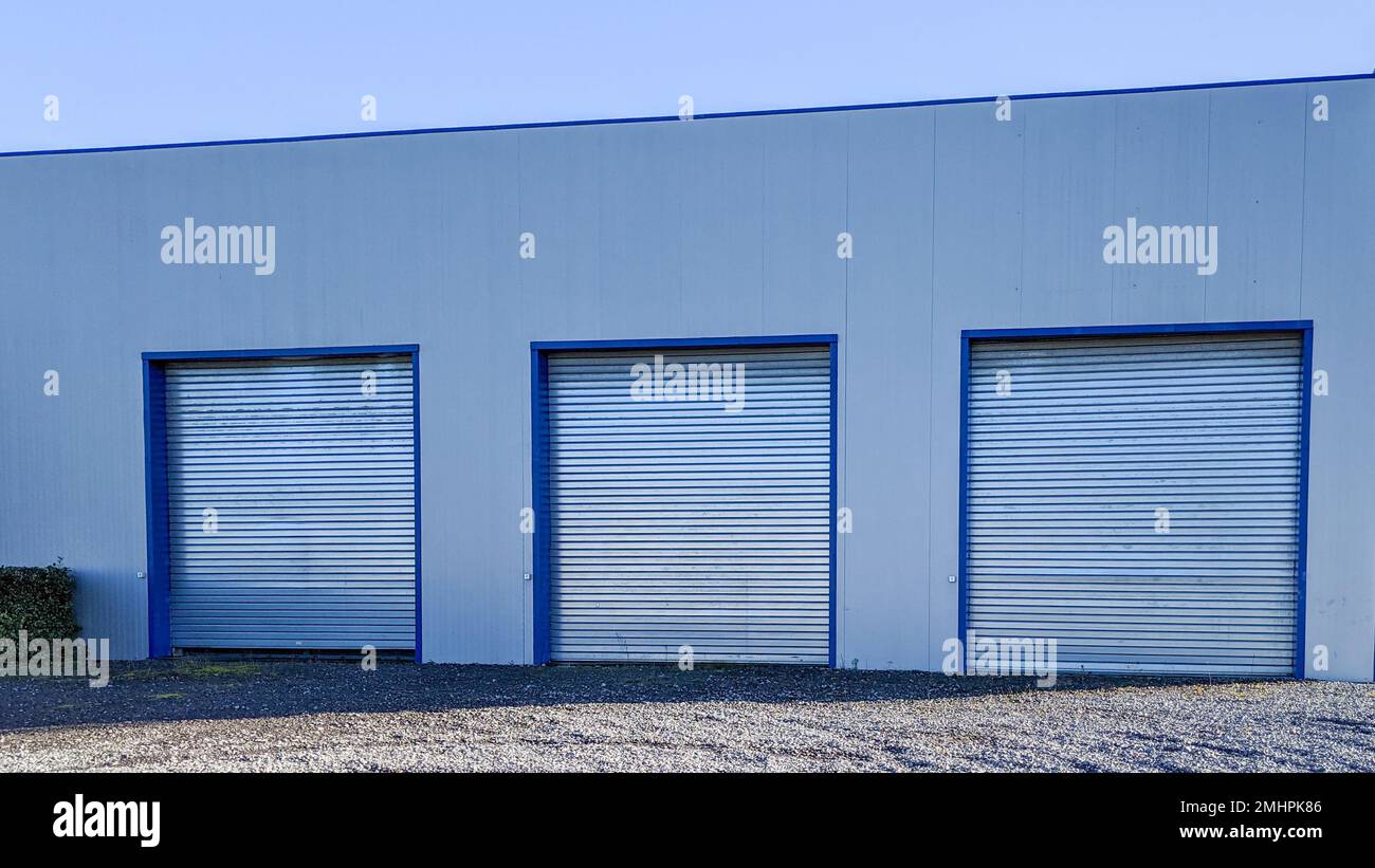 grey Warehouse building with three industrial silver steel door Stock ...