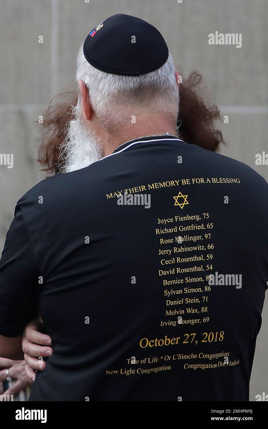 A man, wearing a shirt bearing the names of the 11 people killed when a ...