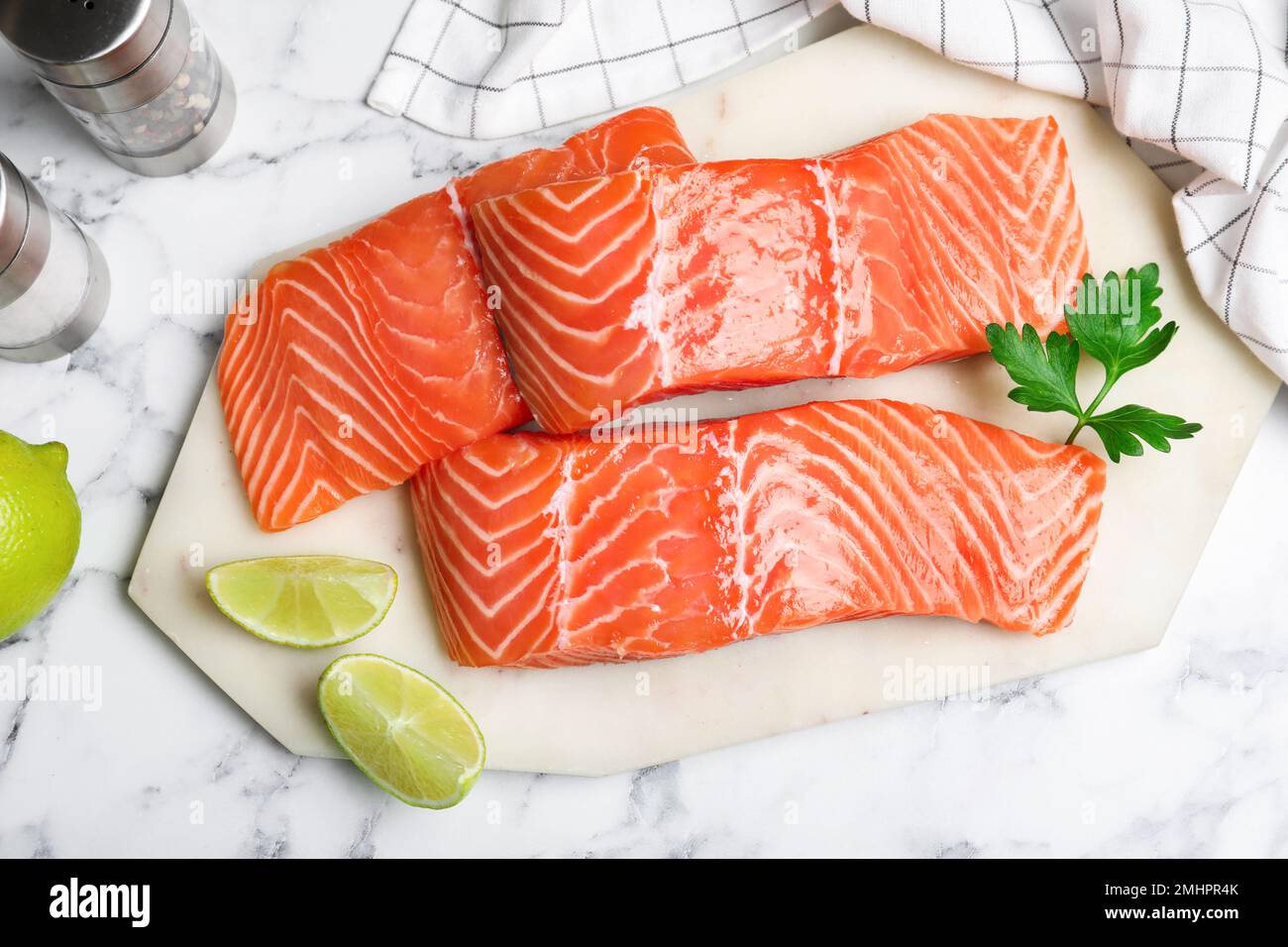 Fresh raw salmon with lime and parsley on white marble table, flat lay ...