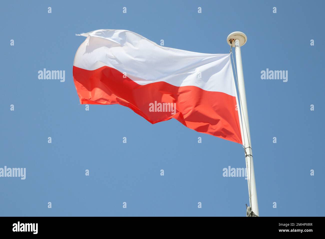 poland flag white red on mat in the wind and blue sky Stock Photo - Alamy