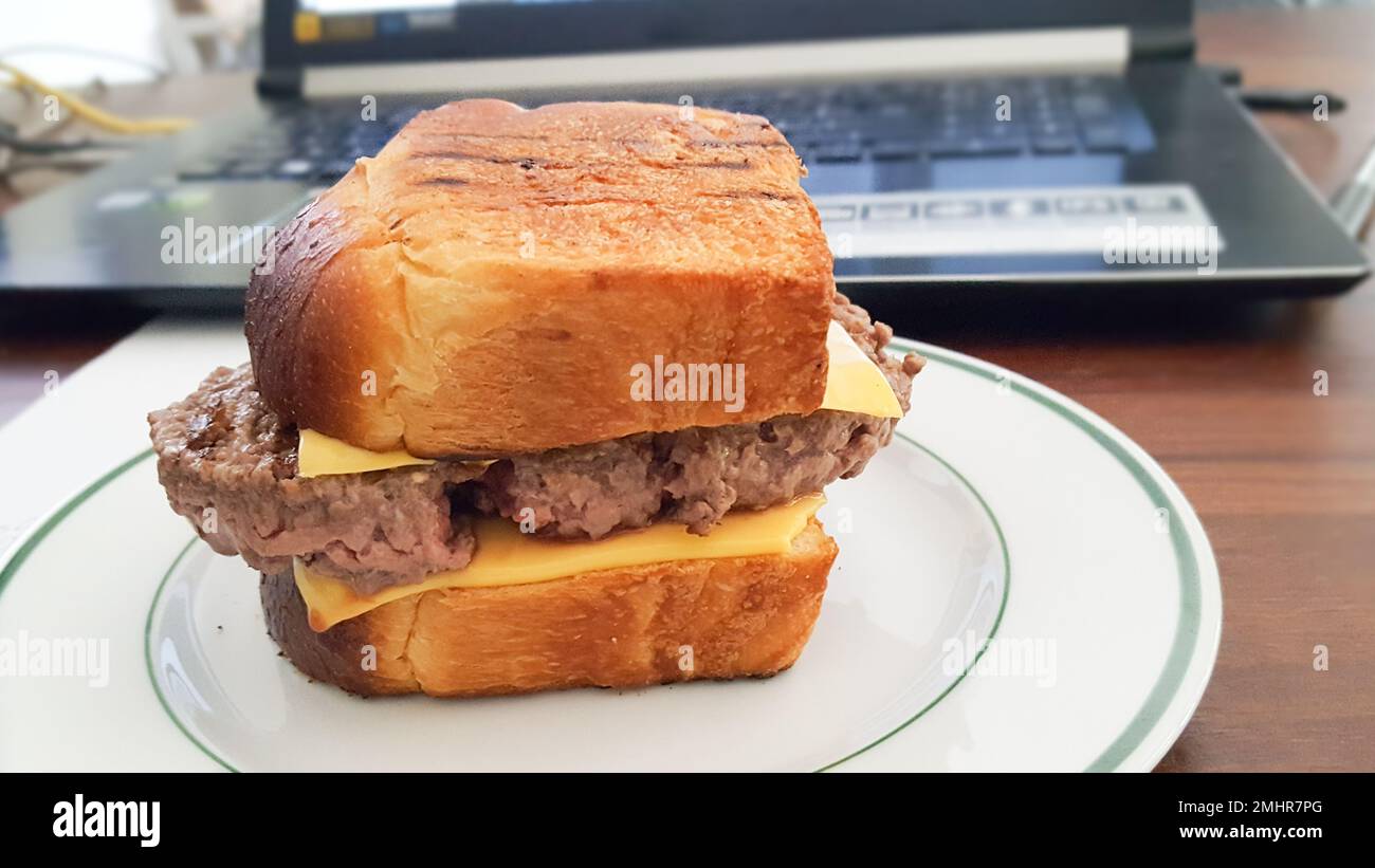 homemade cheese burger on desk in office with laptop background home ...