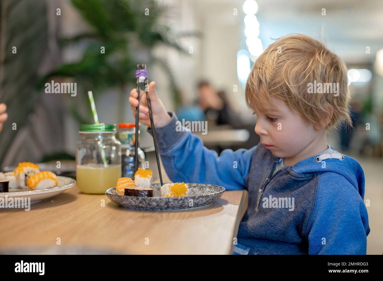 Child, eating japanese sushi and noodles with chopsticks in a ...