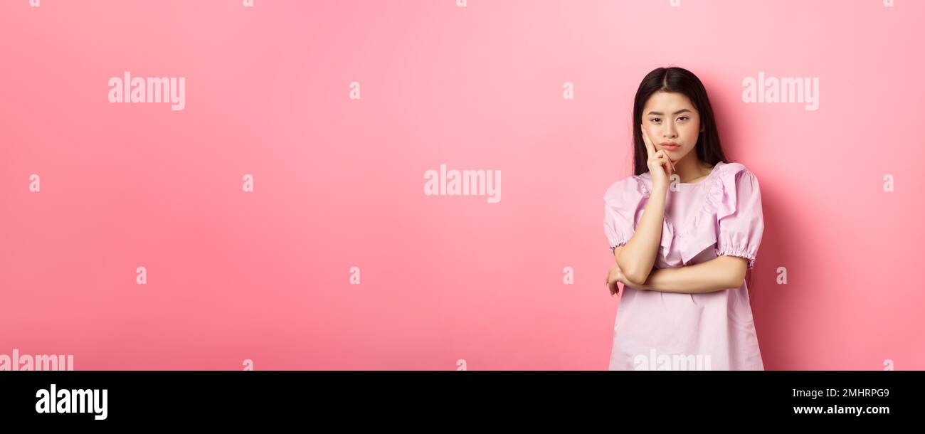 Bored asian teen girl look indifferent at camera, lean face on hand in ...