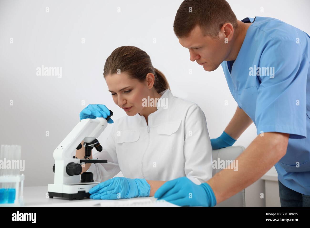 Scientist with microscope at table and colleague in laboratory. Medical ...