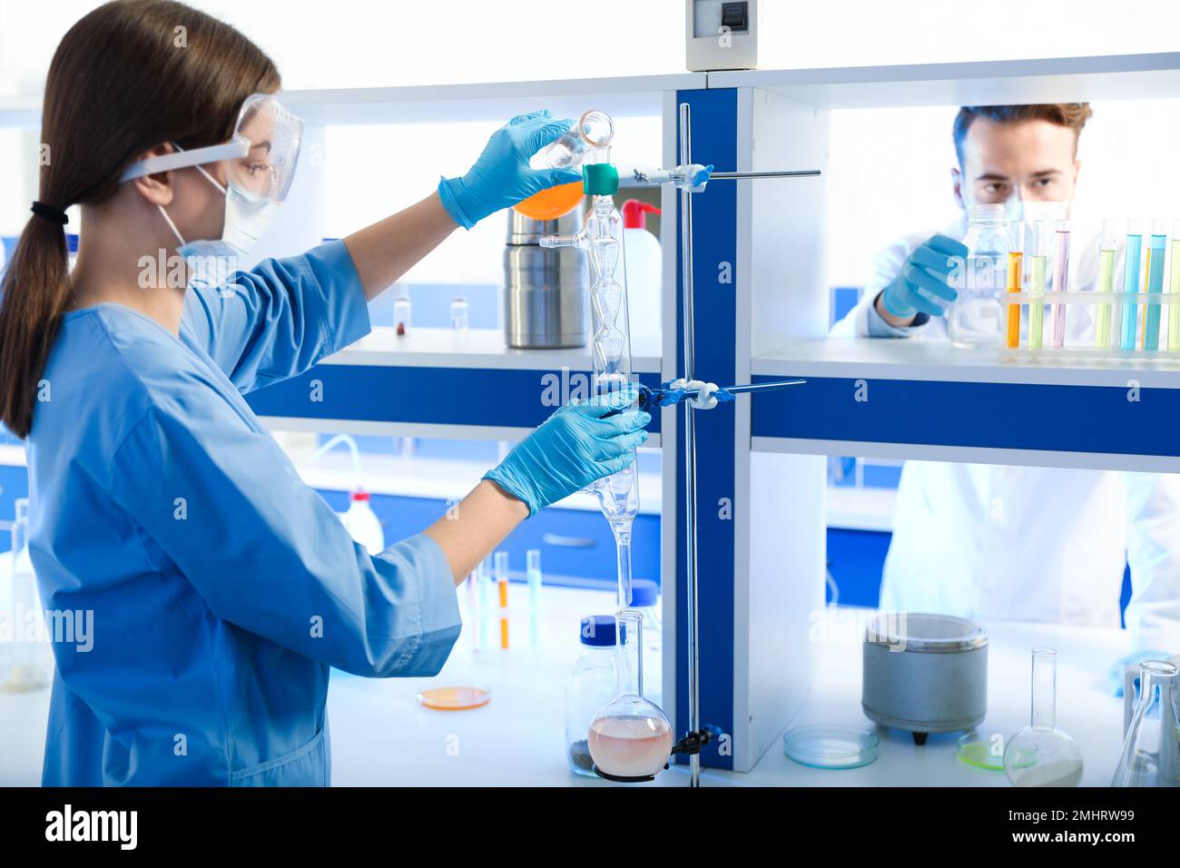 Scientist pouring liquid through glass distillation condenser indoors ...