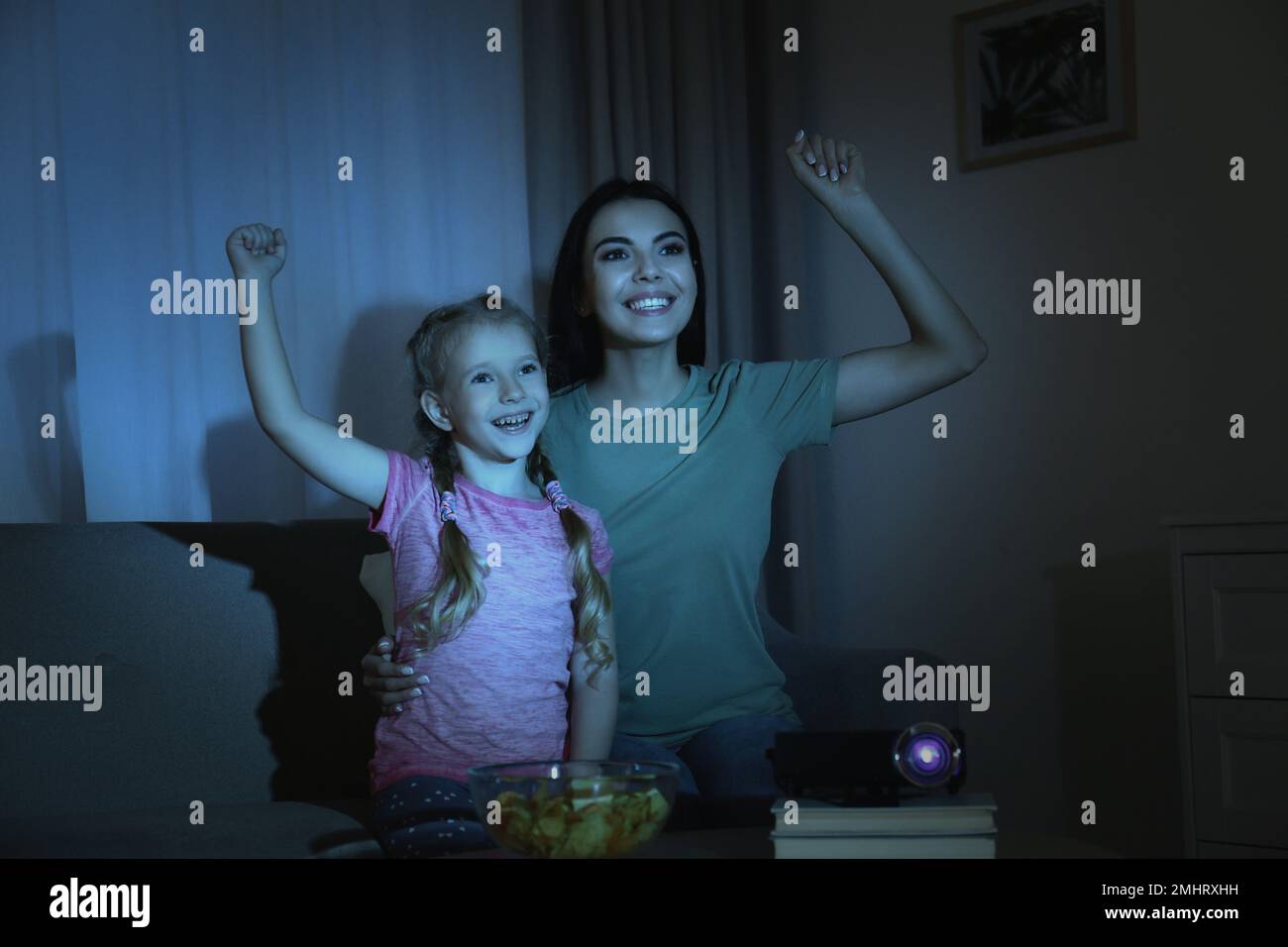 Emotional young woman and her daughter watching TV using video ...