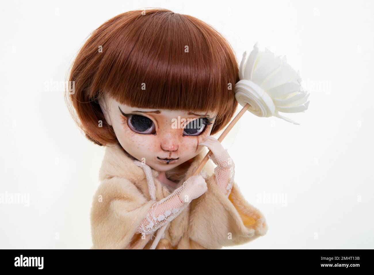 doll scary plastic with tears and flower in hands on white background ...