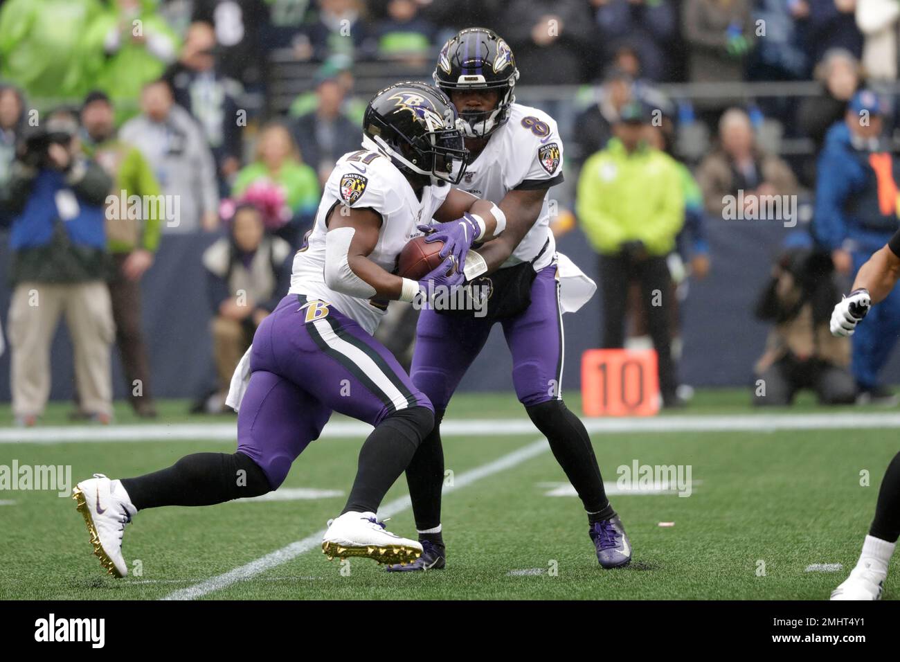 Baltimore Ravens quarterback Lamar Jackson, right, hands off to running ...