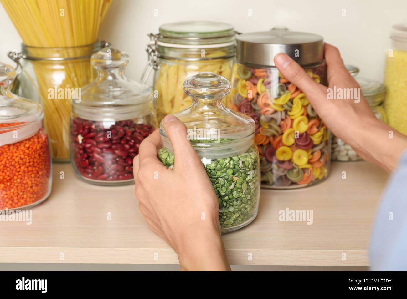 Woman taking jars of different products from wooden shelf, closeup ...