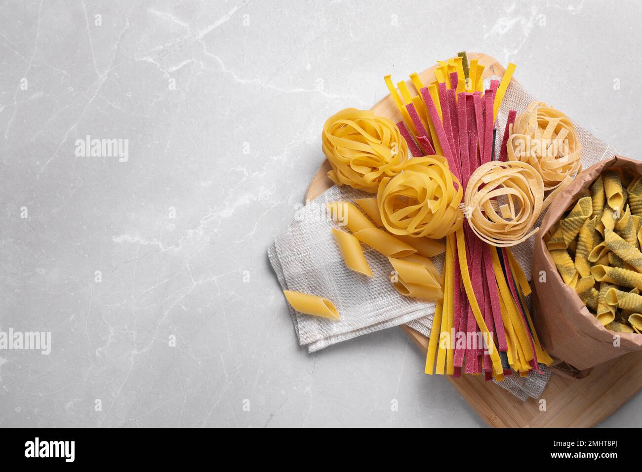 Different types of pasta on light grey marble table, top view. Space ...