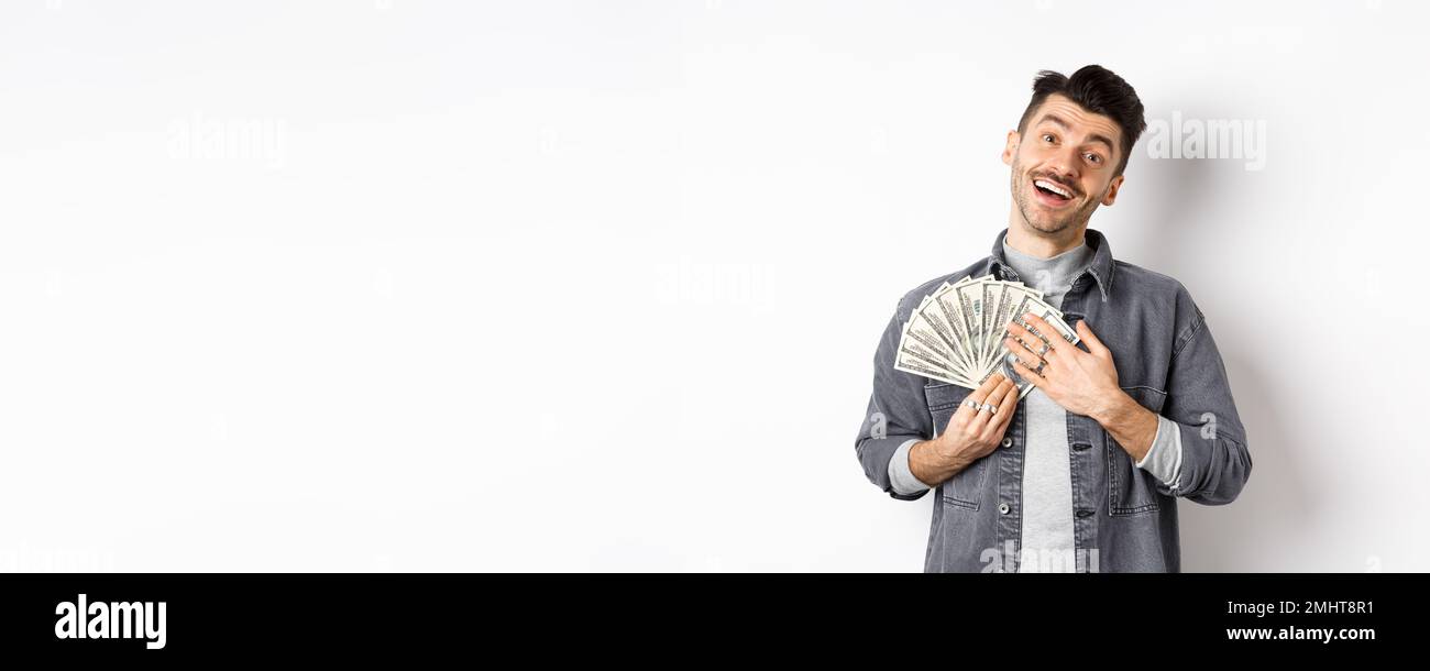 Happy smiling guy making money, hugging dollar bills with pleased ...