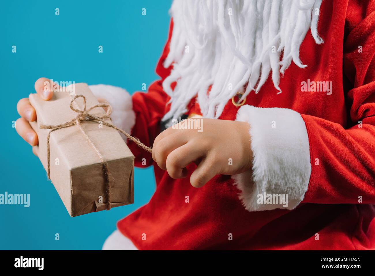 Hands of boy in Santa's costume pulling on string of wrapped gift box ...