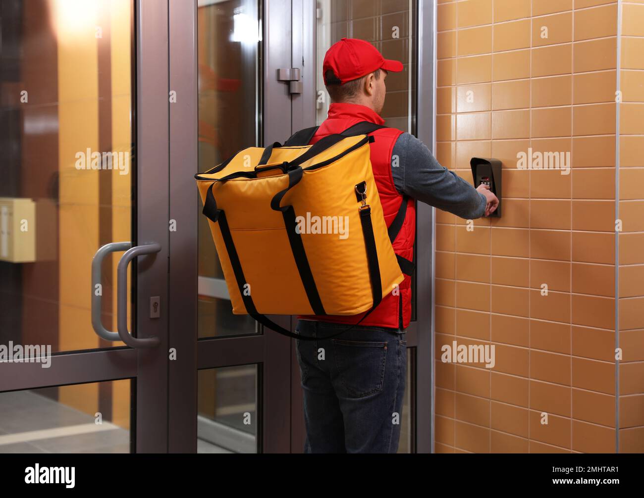 Male courier with thermo bag pushing intercom button. Food delivery ...