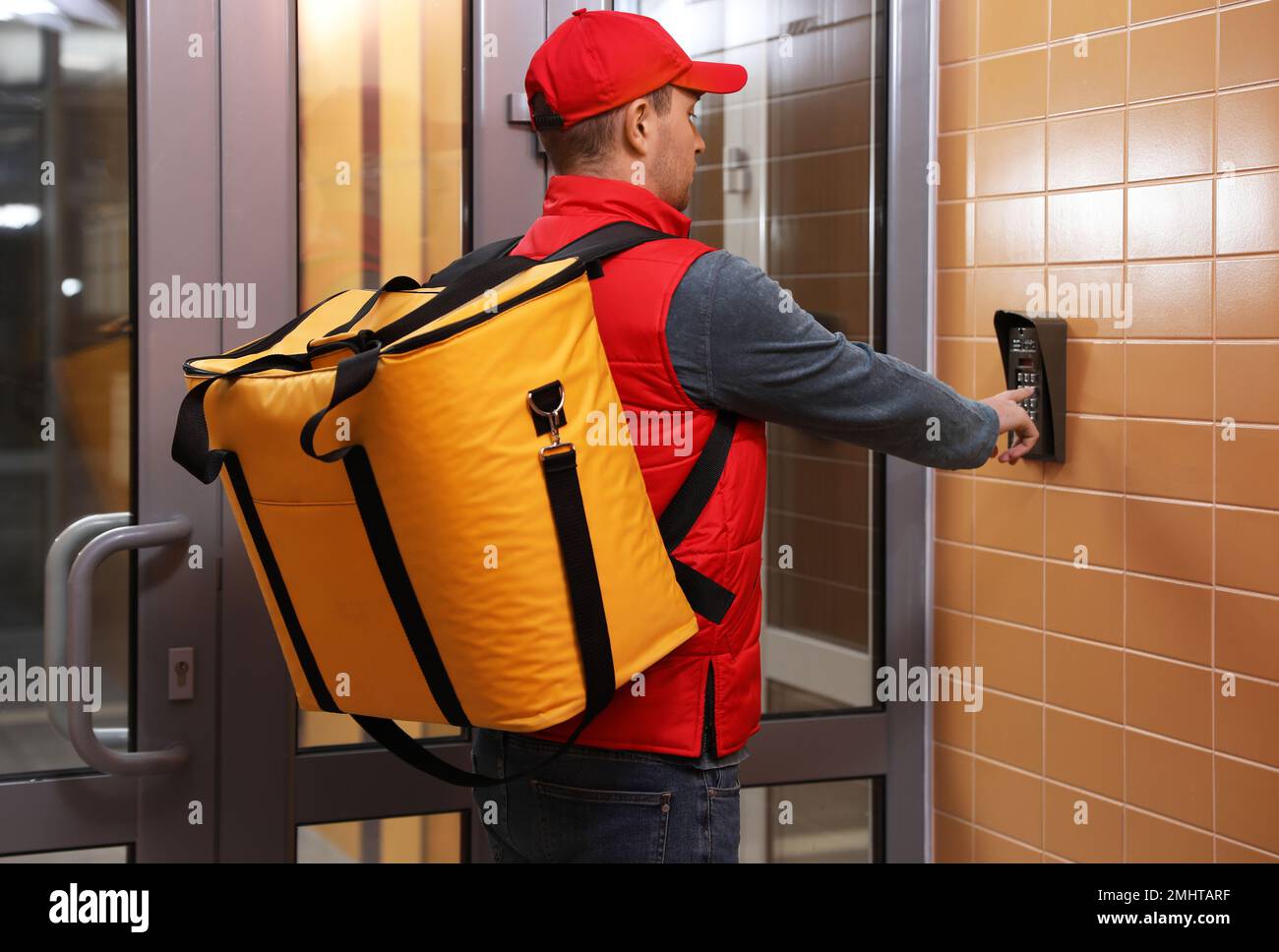 Male courier with thermo bag pushing intercom button. Food delivery ...