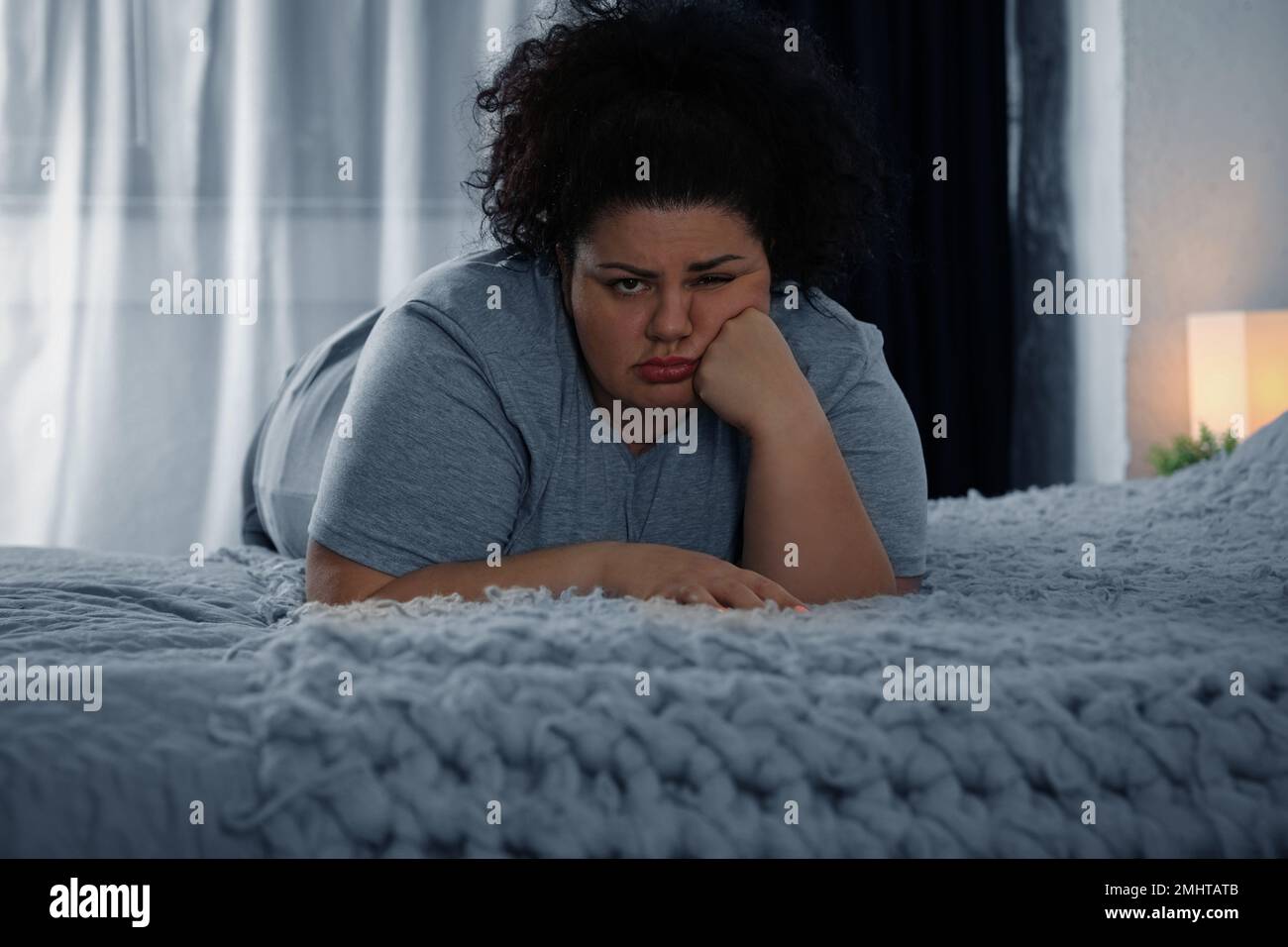 Depressed overweight woman on bed at home Stock Photo - Alamy