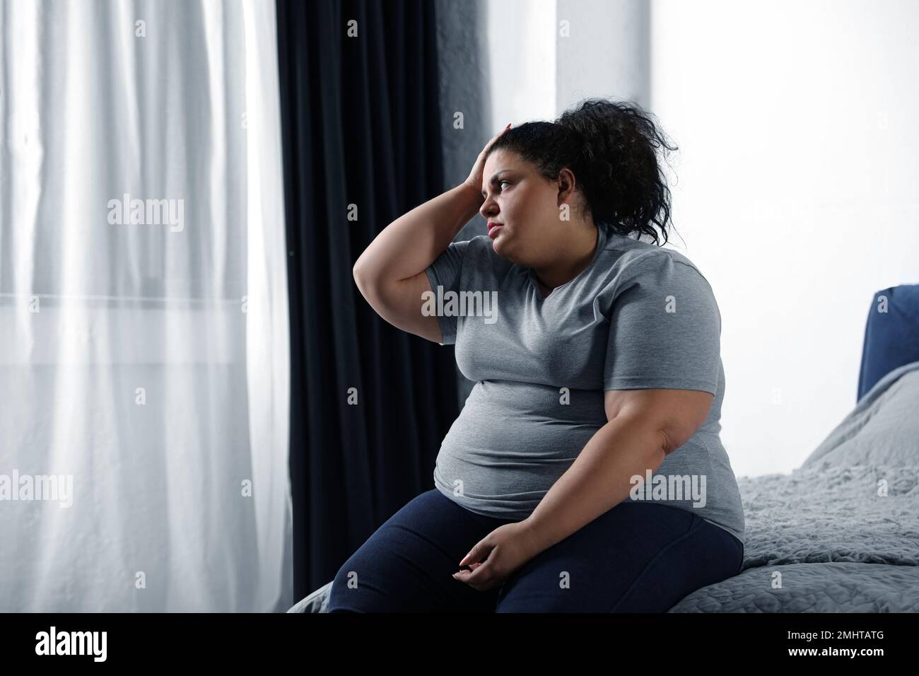 Depressed overweight woman on bed at home Stock Photo - Alamy