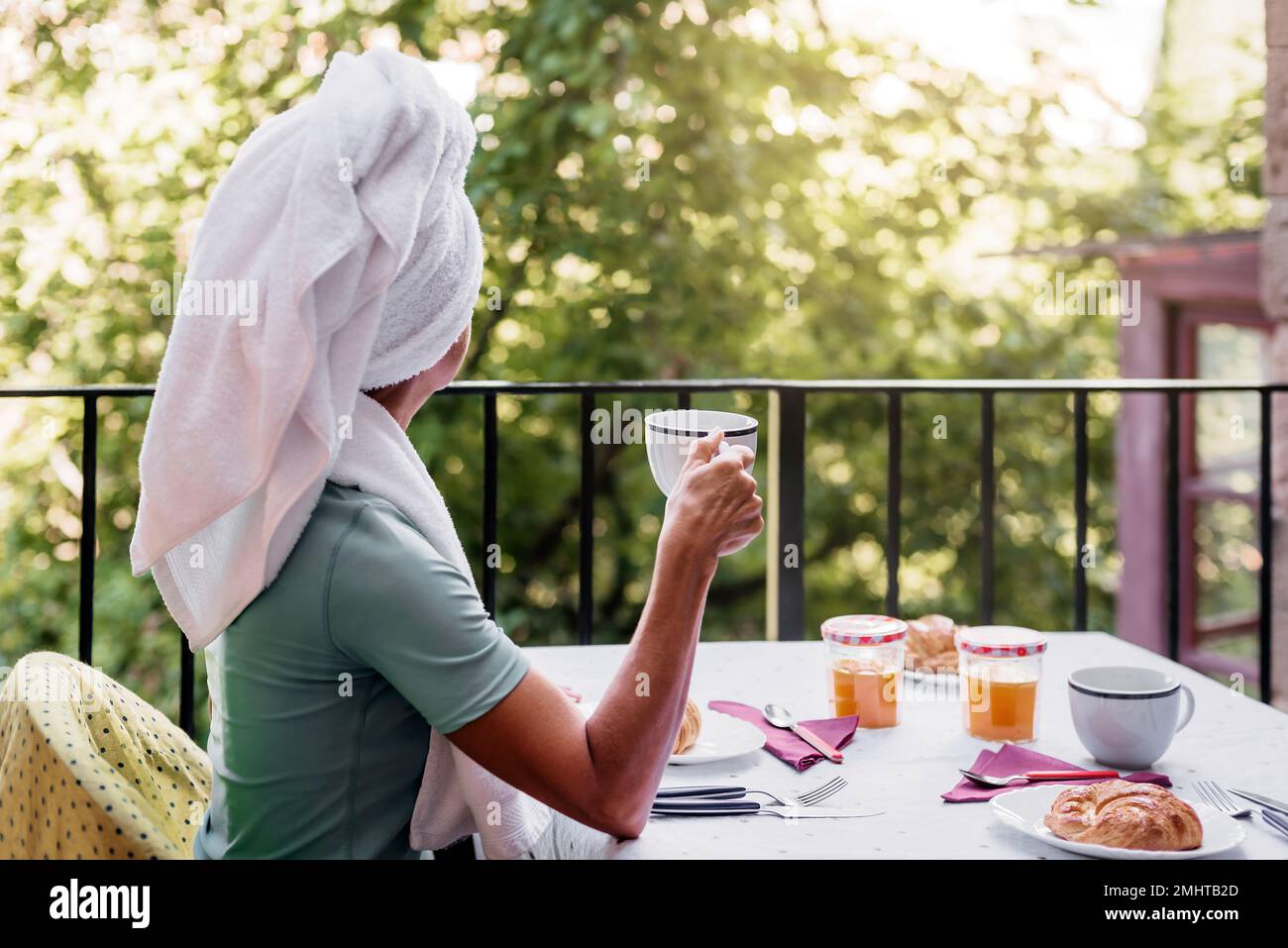a middle-aged caucasian woman has breakfast on the terrace of her house ...