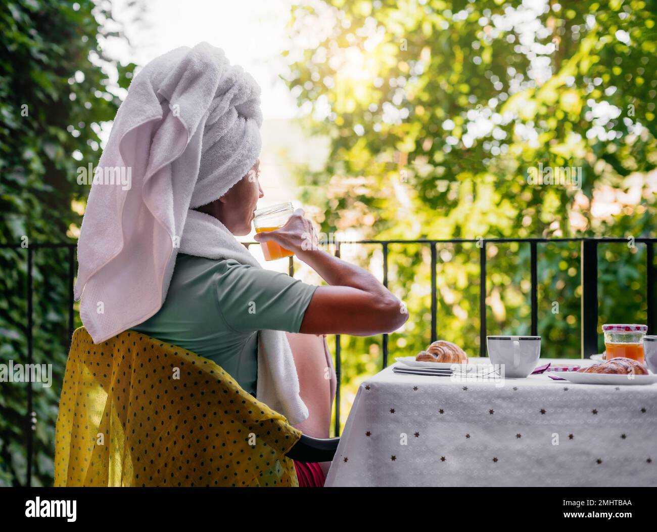 a middle-aged caucasian woman has breakfast on the terrace of her house ...