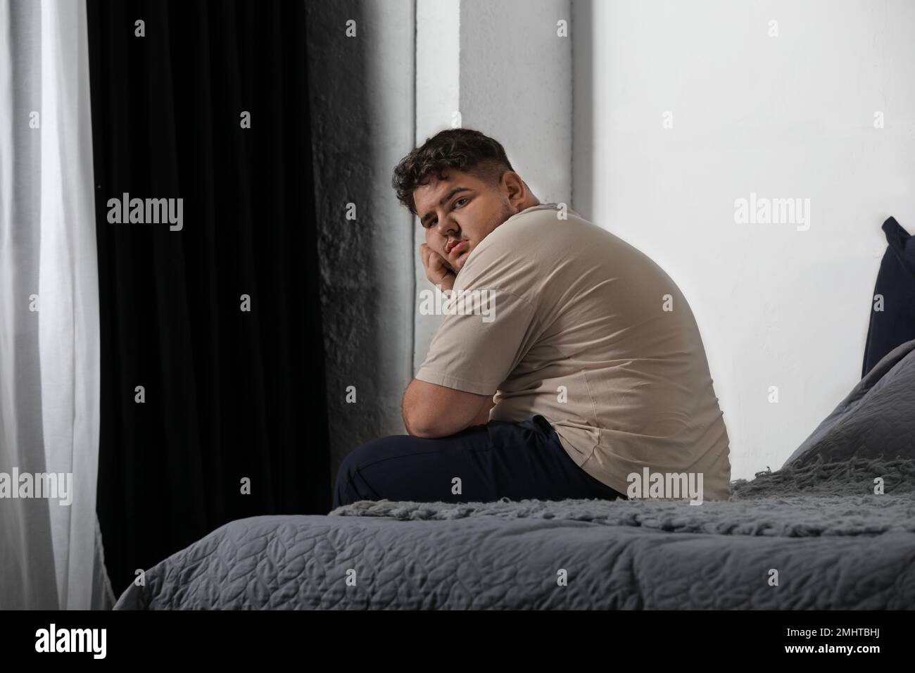 Depressed overweight man on bed at home Stock Photo - Alamy