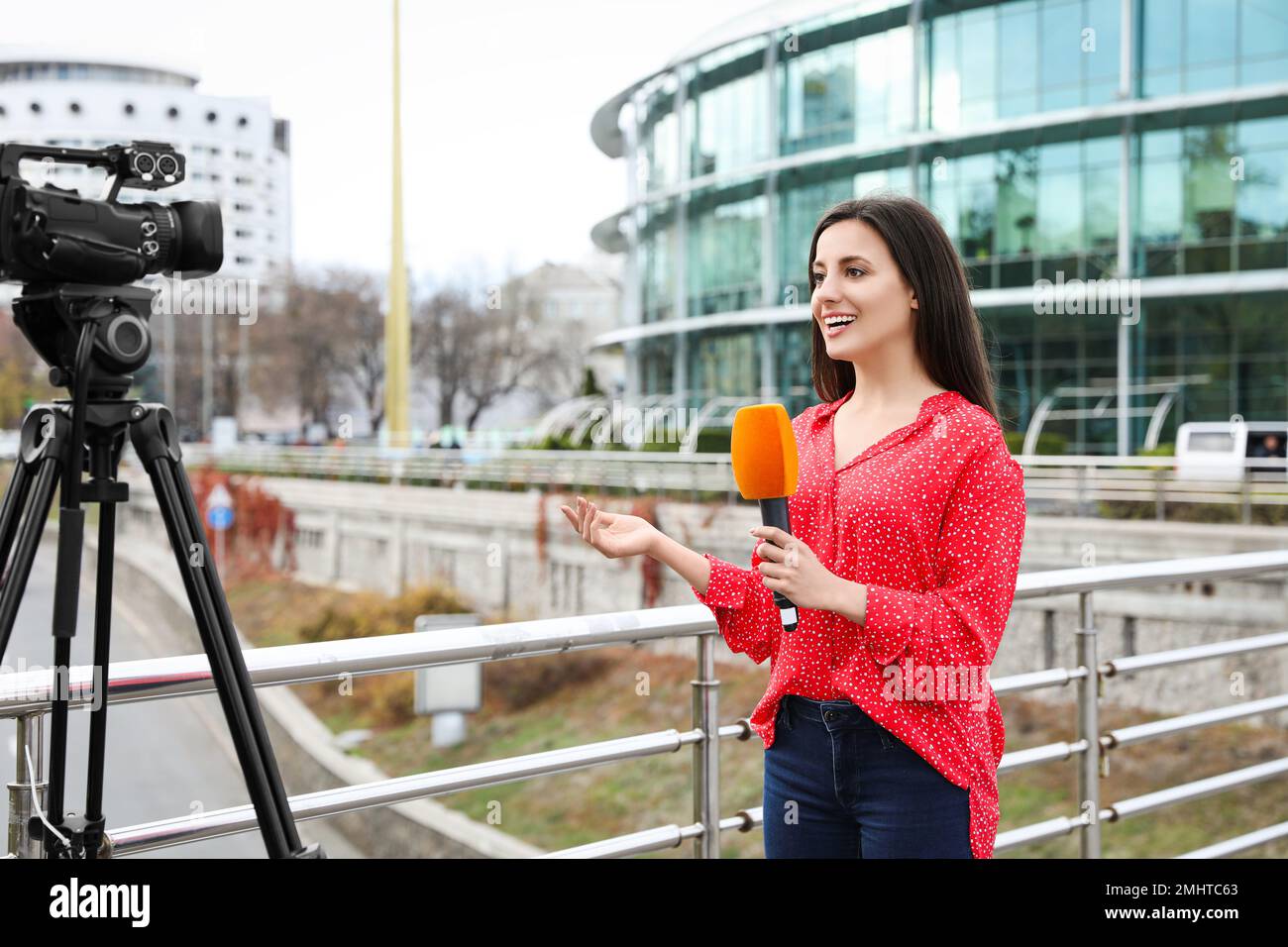 Young female journalist with microphone working on city street Stock ...