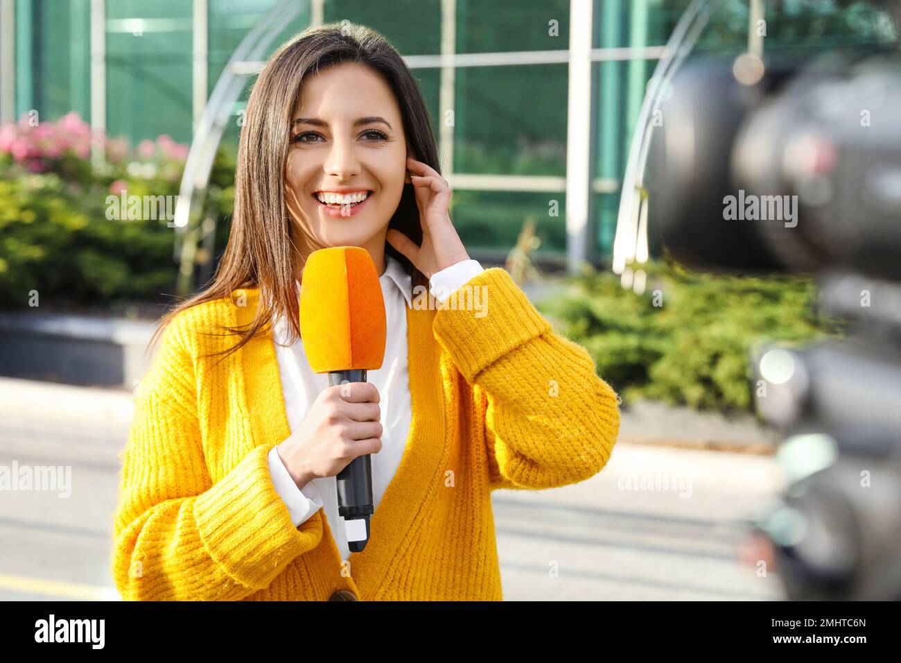 Young female journalist with microphone working on city street Stock ...