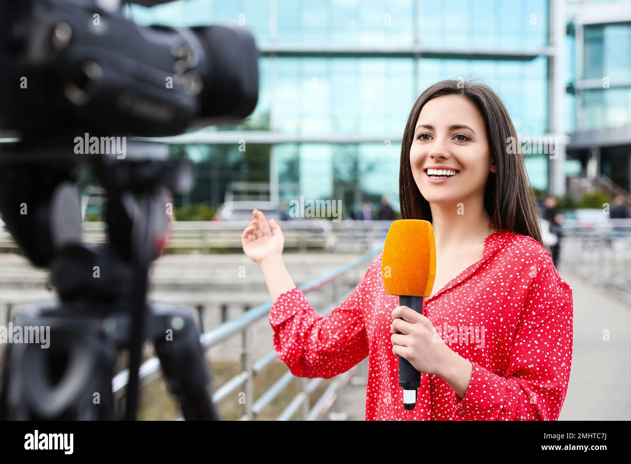 Young female journalist with microphone working on city street Stock ...