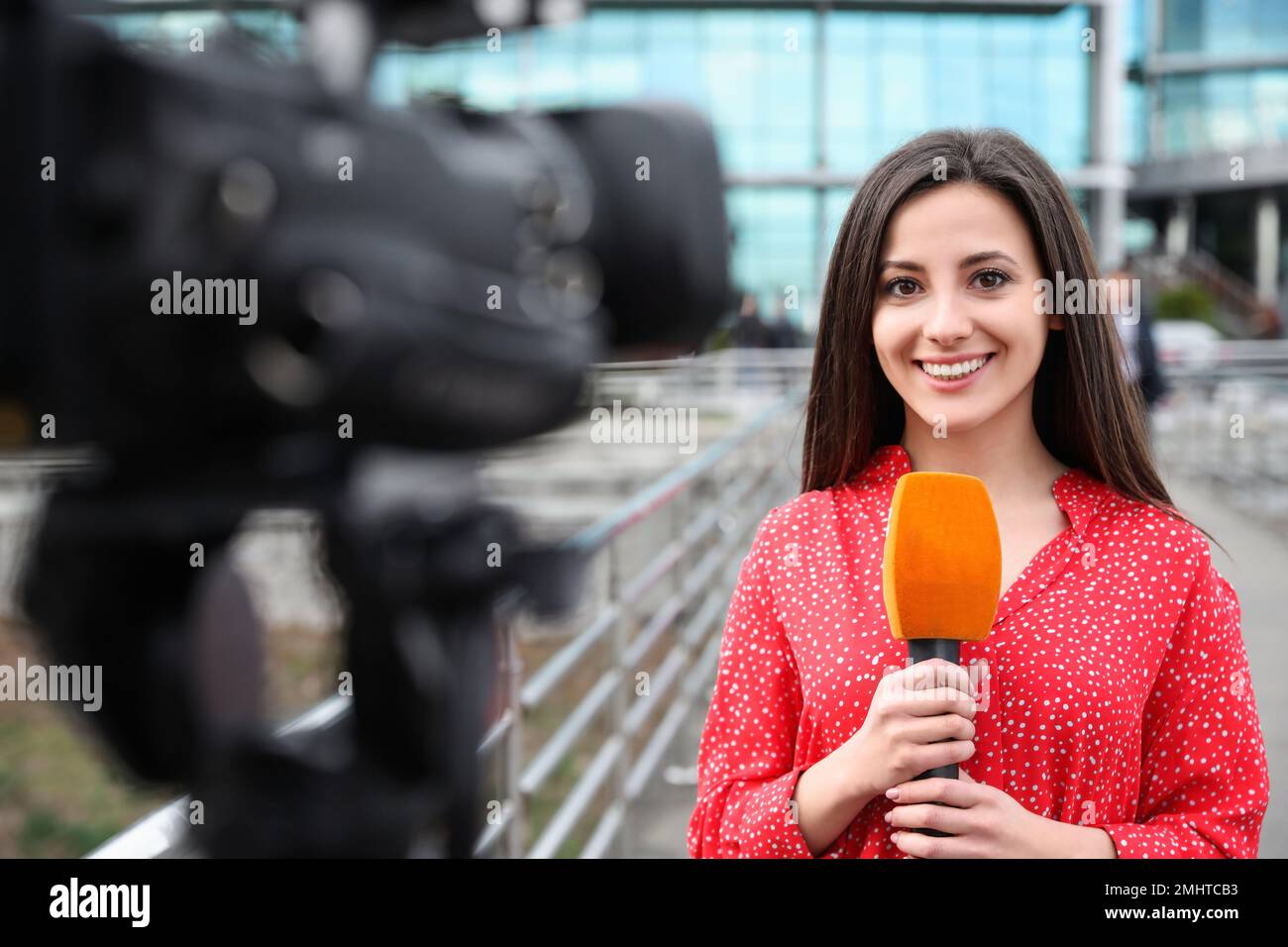Young female journalist with microphone working on city street Stock ...