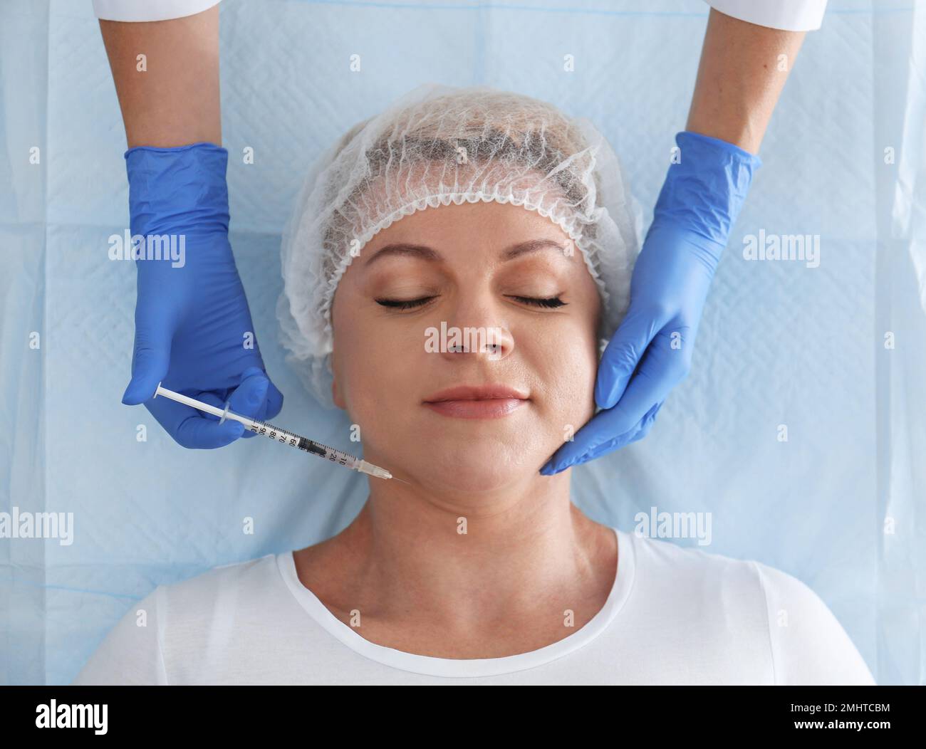 Mature woman with double chin receiving injection in clinic, above view ...