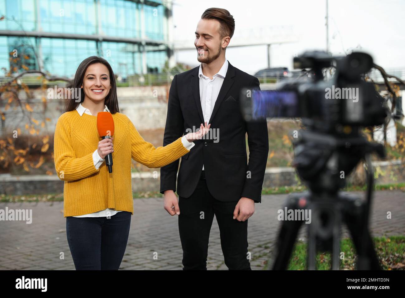 Young journalist interviewing businessman on city street Stock Photo ...